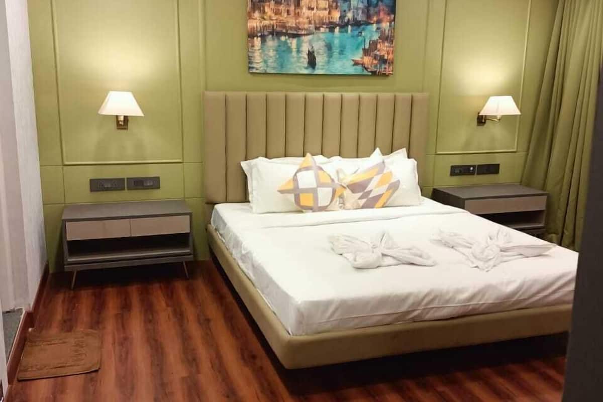 Quarto de hotel com cama, duas mesas de cabeceira, um quadro e um ventilador de teto.