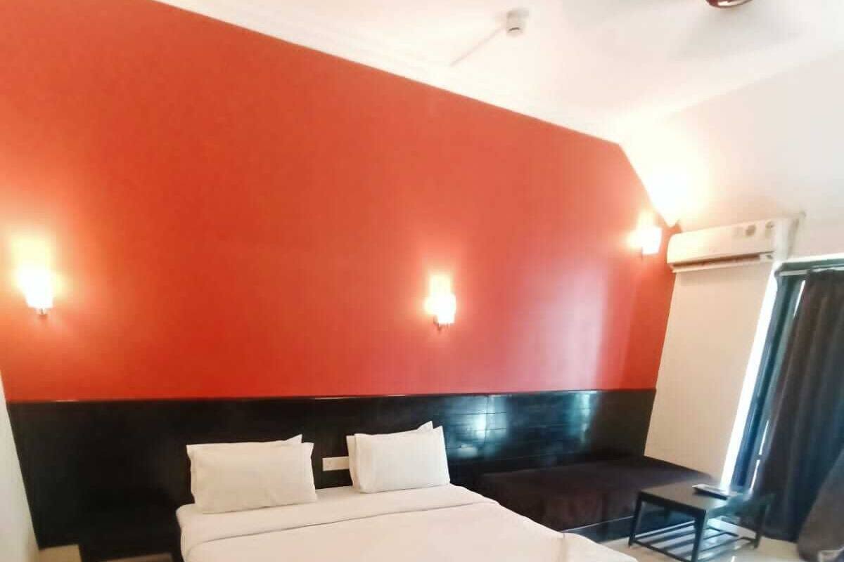 Quarto de hotel com uma cama grande, cabeceira preta e parede de destaque vermelha.