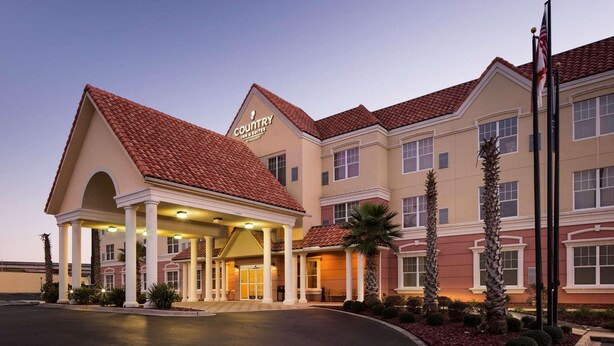 Um hotel com entrada coberta, vários andares e telhado de telhas vermelhas.