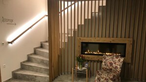 Uma escadaria com uma placa de recepção, uma parede de madeira com lareira e uma poltrona floral.