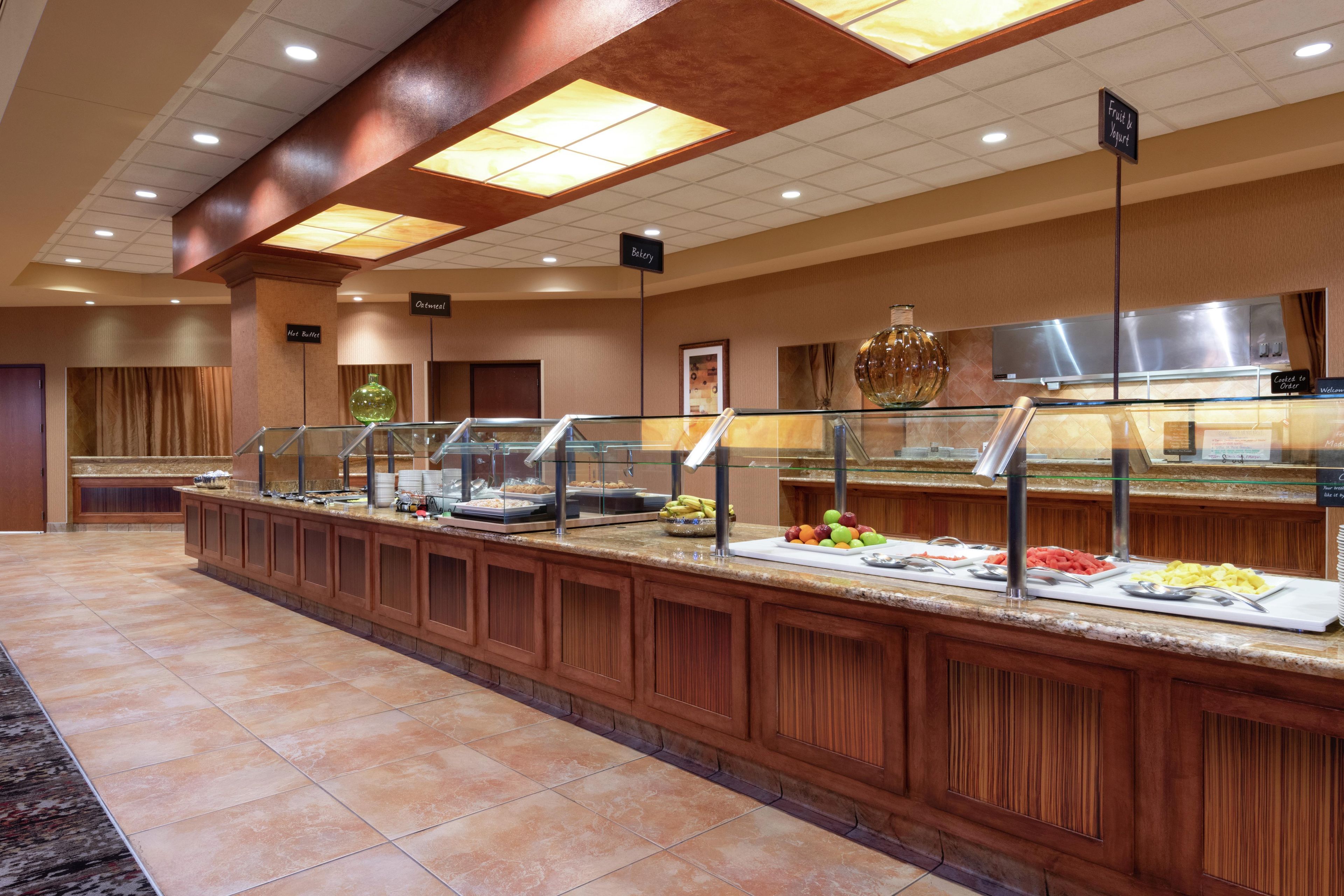 Uma área de buffet com várias estações de comida, incluindo buffet quente e uma estação de aveia.