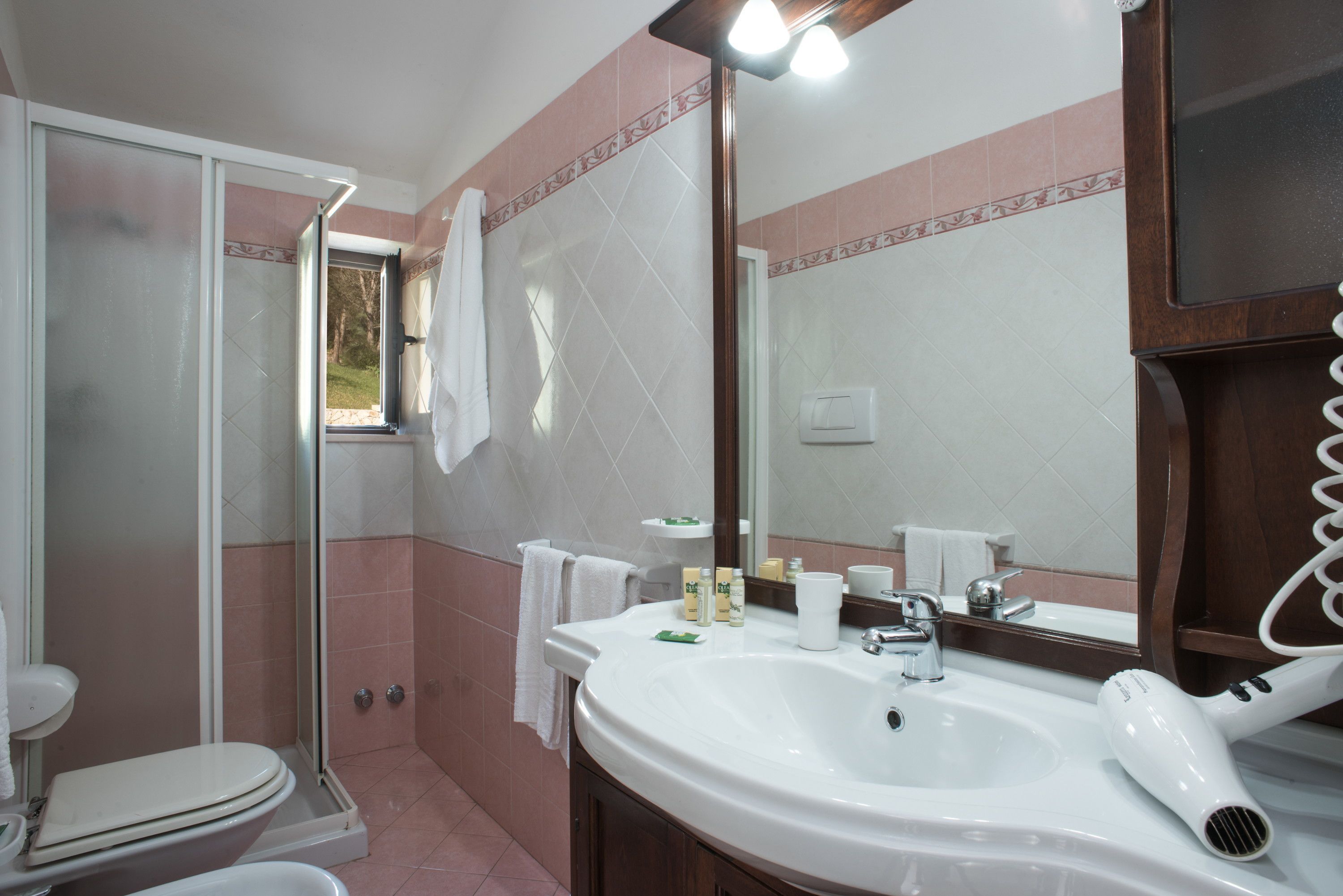 Casa de banho com chuveiro, sanita, lavatório e secador de cabelo.