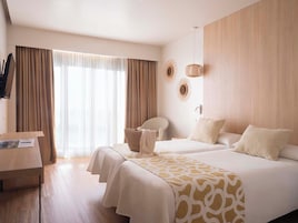 Quarto de hotel com duas camas, uma escrivaninha e uma cadeira.