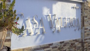 Placa de "Casa Valeria" com parede de pedra e planta em vaso.