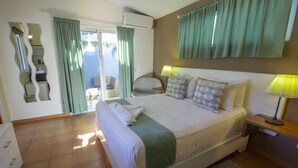 Quarto com cama, escrivaninha, cadeira, espelho e janela com cortinas.