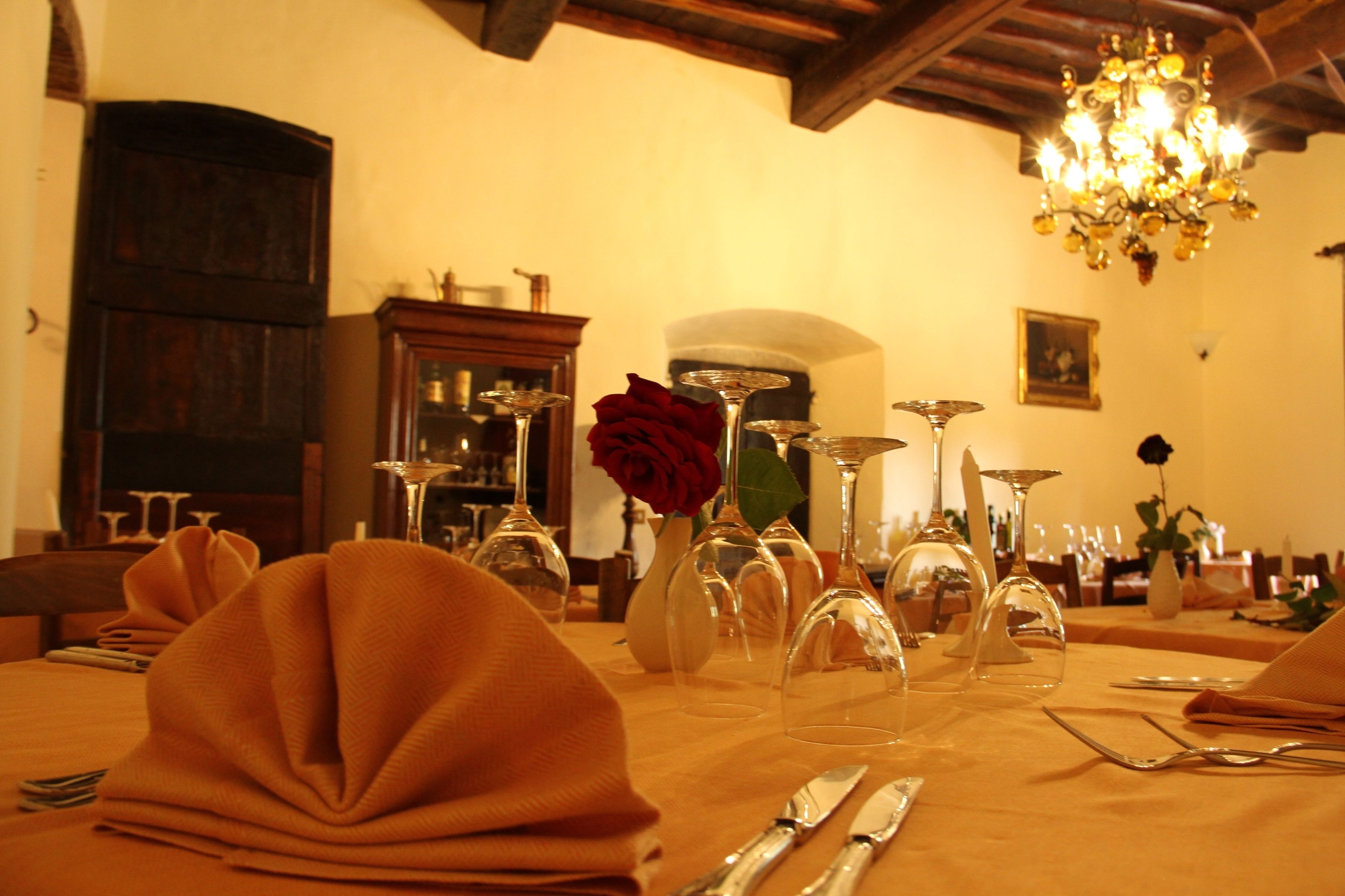 Mesa de jantar posta com taças de vinho, uma rosa e um candelabro.