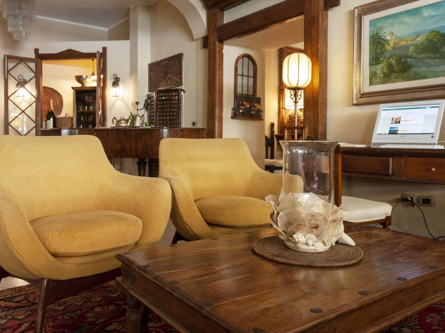 Quarto com duas poltronas amarelas, uma mesa de centro de madeira com um objeto decorativo, um laptop e um quadro na parede.