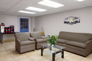 Uma área de espera com dois sofás, uma mesa de centro, uma porta azul e uma obra de arte floral suspensa na parede.