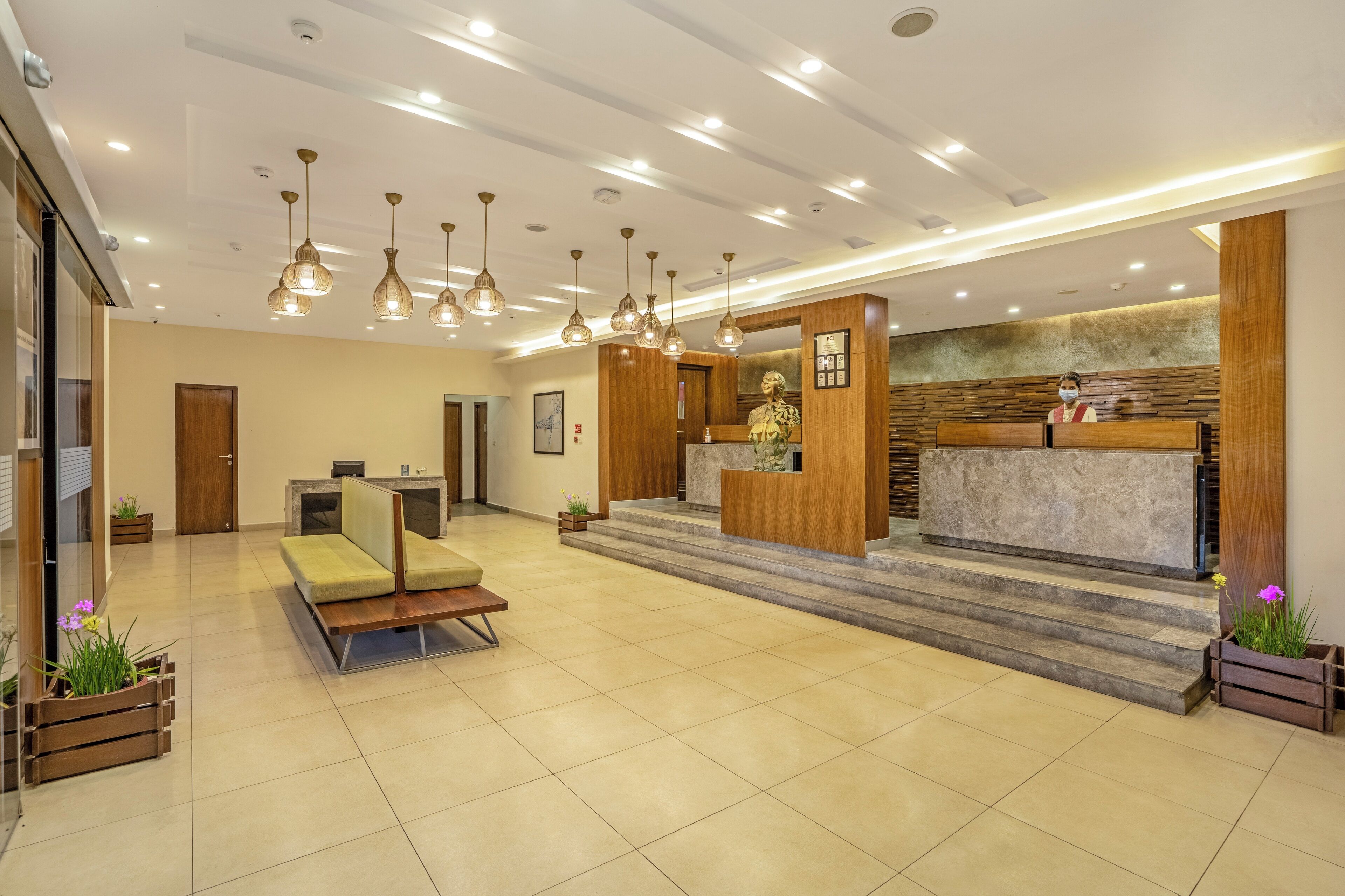 Uma área de recepção de hotel com um balcão de madeira, um espaço de estar acolchoado e um design de teto moderno.