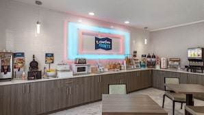 Cozinha moderna com bancada para refeições, micro-ondas, torradeira e diversos alimentos.