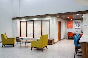 Um lobby moderno com poltronas amarelas, uma mesa de centro e um balcão de recepção.