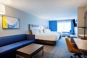 Quarto de hotel com cama, sofá, escrivaninha e televisão.