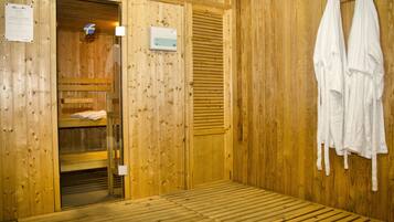 Um espaço sauna de madeira com bancos, um banco na entrada e duas toalhas brancas penduradas na parede.