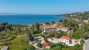 Um imóvel costeiro com piscina, vários edifícios e vista para o mar.