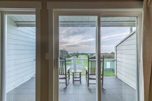 Varanda com vista para um campo de golfe, uma mesa e duas cadeiras.