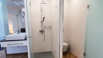 Uma casa de banho moderna com cabine de duche em vidro, lavatório branco e sanita.