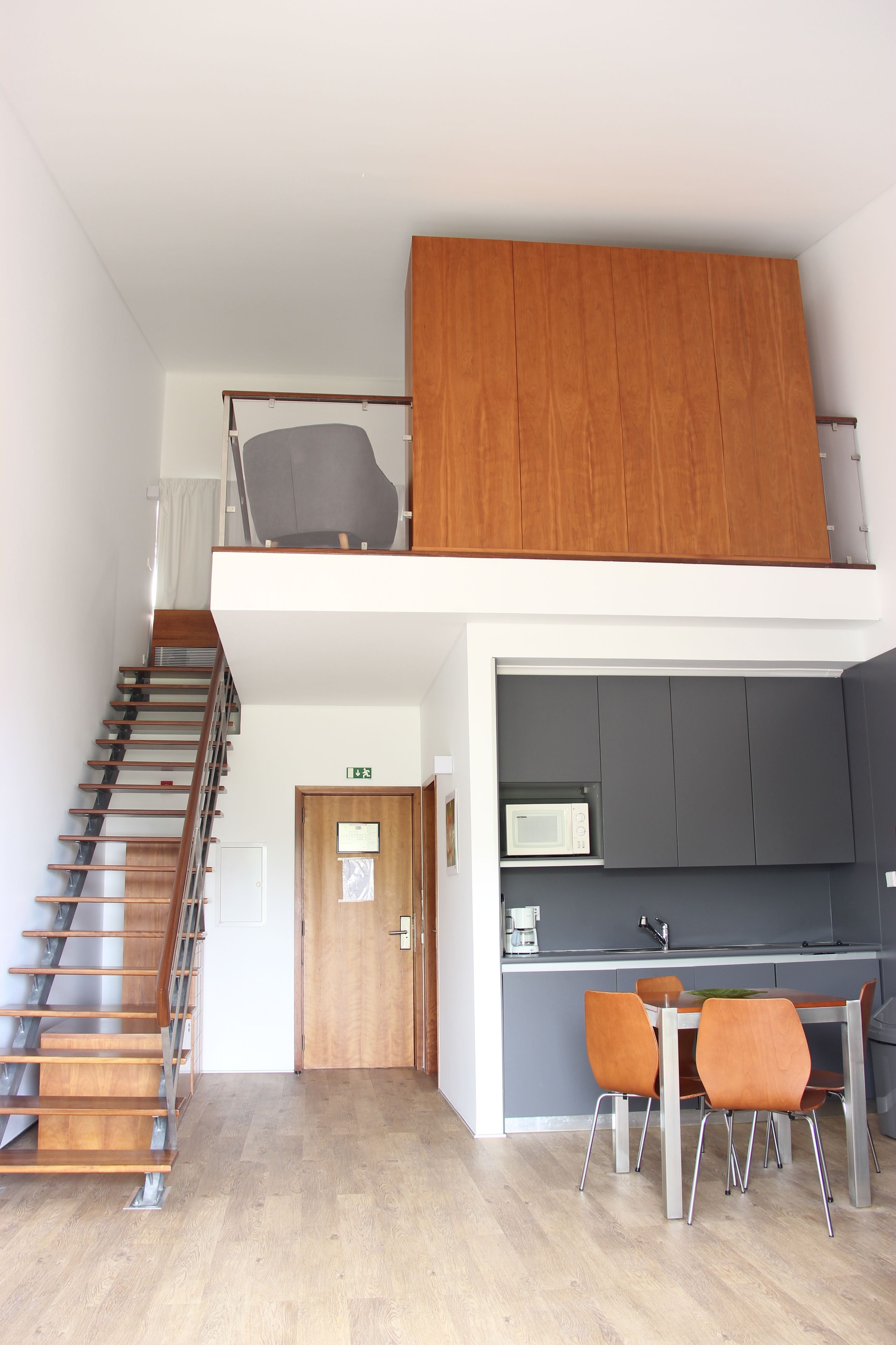 Um apartamento moderno com escada, área de cozinha e espaço para refeições.