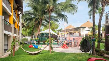Espaço de recreação infantil com escorregadores, balanços e rede.