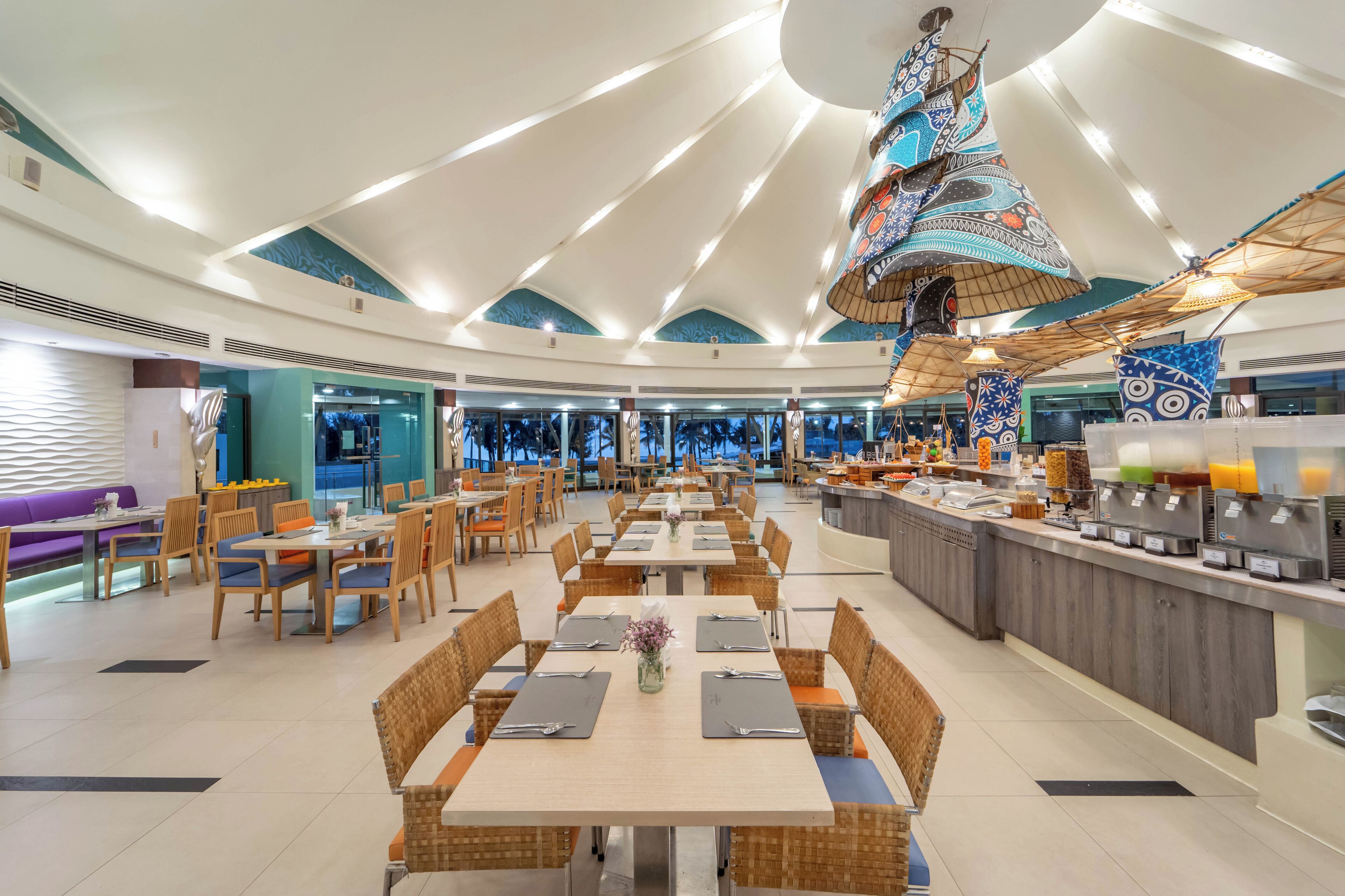 Uma ampla sala de jantar com pé direito alto, iluminação moderna e um buffet central.