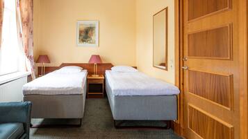 Quarto de hotel com duas camas de solteiro, uma porta de madeira e uma obra de arte emoldurada na parede.