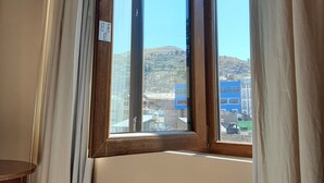 Quarto com uma grande janela, cortinas e porta de madeira.