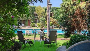 Área da piscina com espreguiçadeiras e uma estátua.