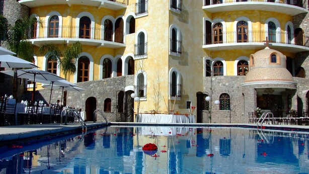 Um hotel com piscina, várias varandas e fachada de pedra.