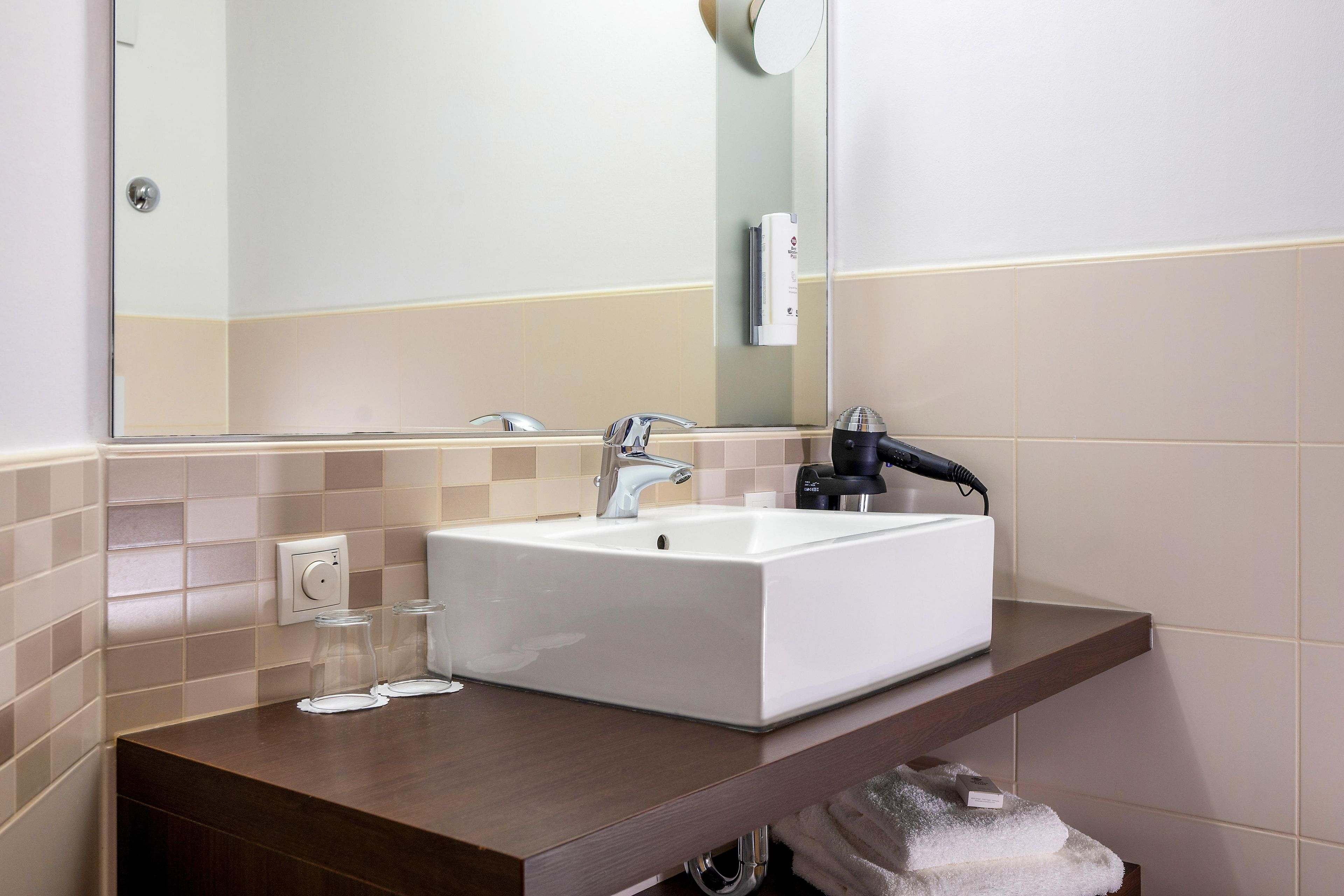 Casa de banho com lavatório branco, espelho e porta-toalhas.