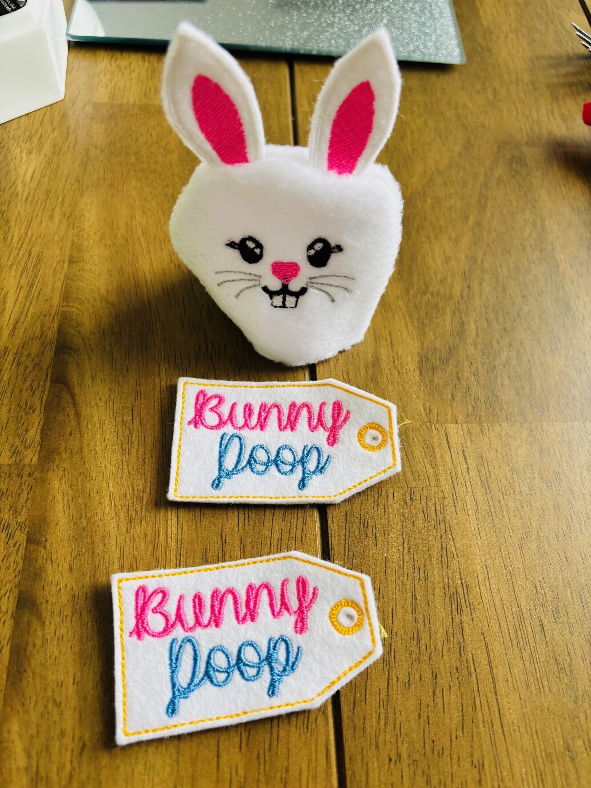 Um brinquedo de pelúcia com corpo branco e orelhas cor-de-rosa, e duas etiquetas com o texto "Bunny Loop".