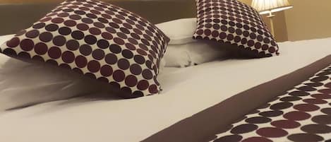 Uma cama com almofadas estampadas e colcha listrada.