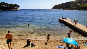 Uma praia com águas cristalinas, barcos e pessoas aproveitando a orla.