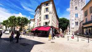 Rua com um café chamado 'Matisse' e um edifício de pedra com uma placa 'Henry's Bar'.