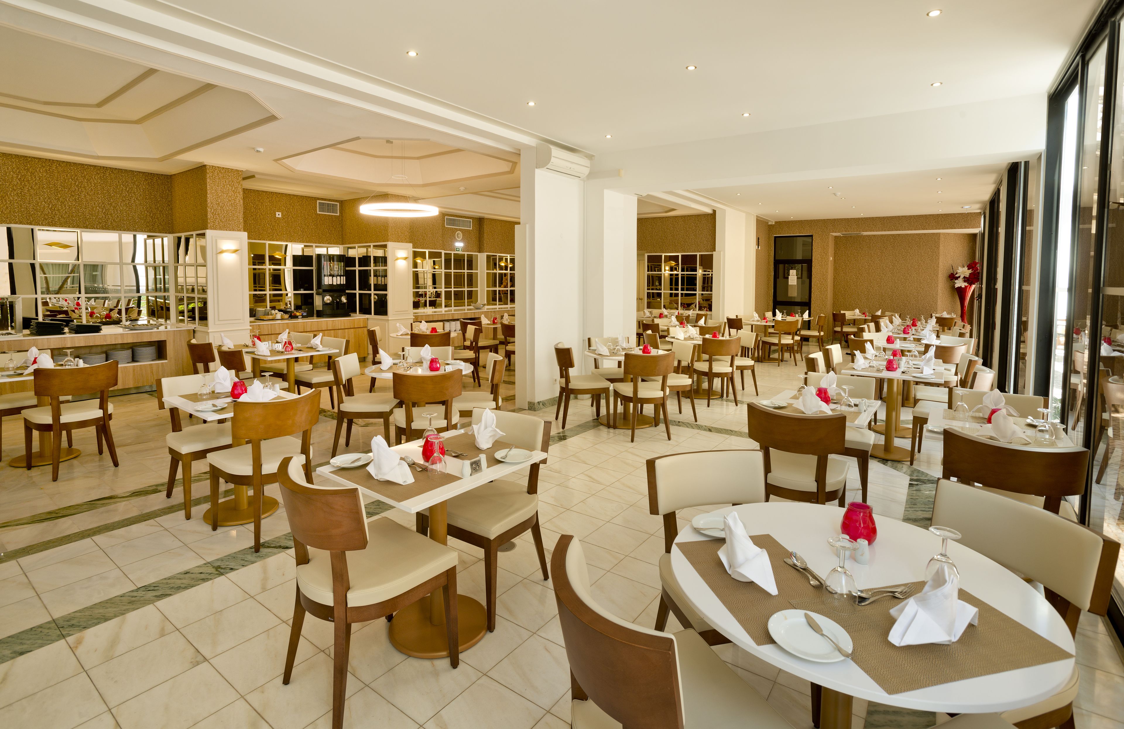Um restaurante amplo com várias mesas e cadeiras, janelas grandes e um design de interiores moderno.
