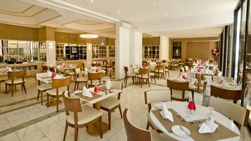 Um restaurante amplo com várias mesas e cadeiras, janelas grandes e um design de interiores moderno.
