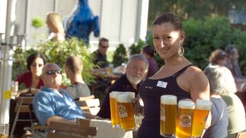 Mulher segurando três copos de cerveja em um evento ao ar livre.