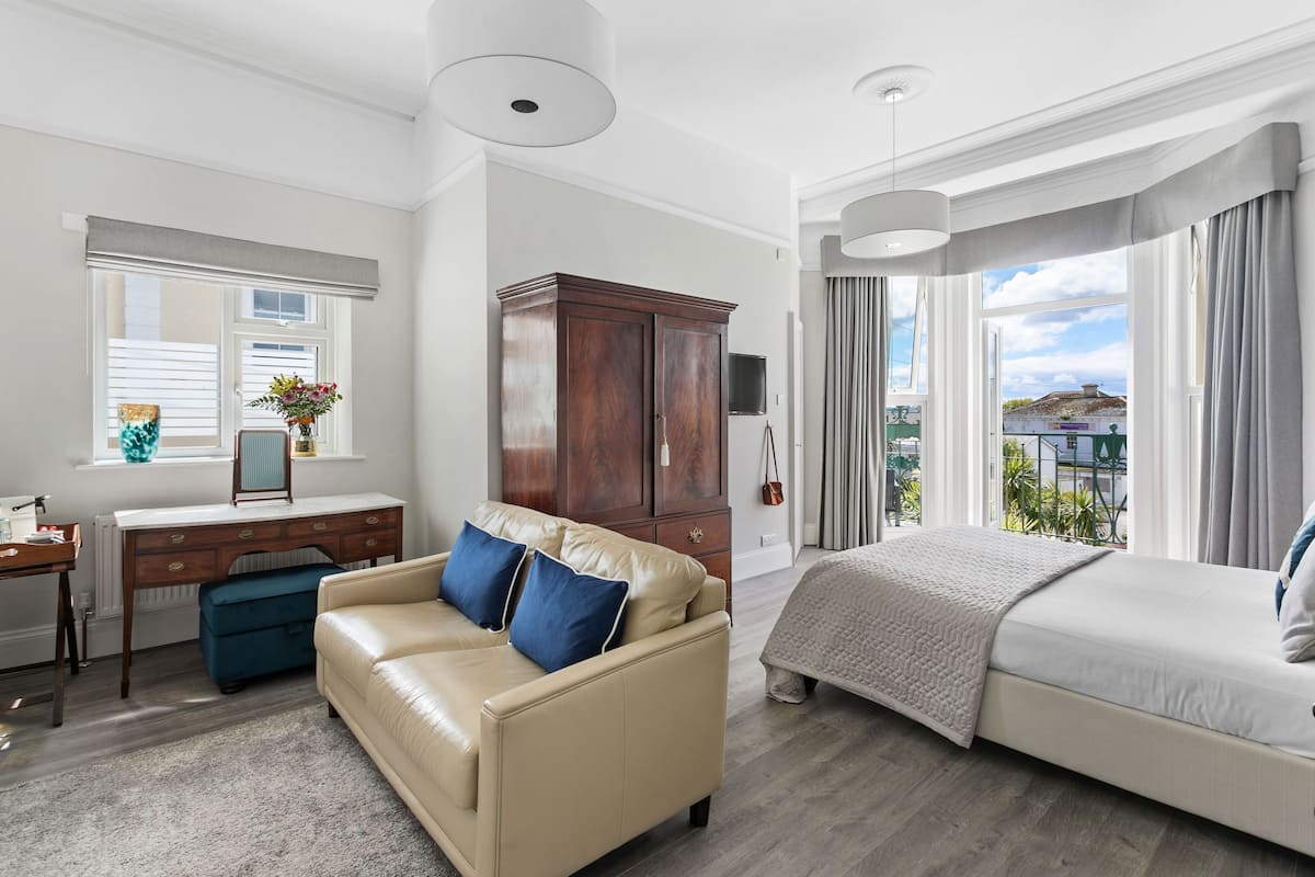 Quarto de hotel moderno com uma cama grande, um sofá, uma escrivaninha e um guarda-roupa.