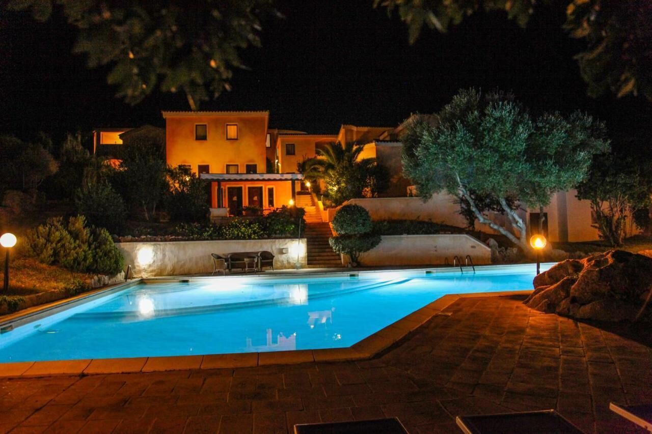 Piscina à noite com um edifício ao fundo.
