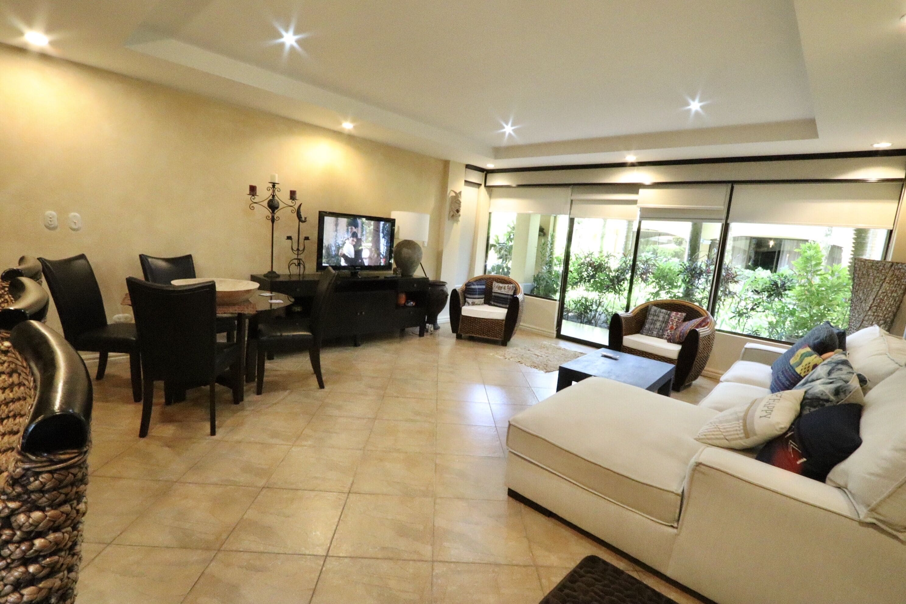 Uma sala de estar ampla com área de jantar, sofá e televisão.