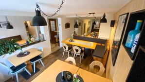 Uma cozinha moderna com ilha central, luminárias pendentes e uma área de jantar com cadeiras.