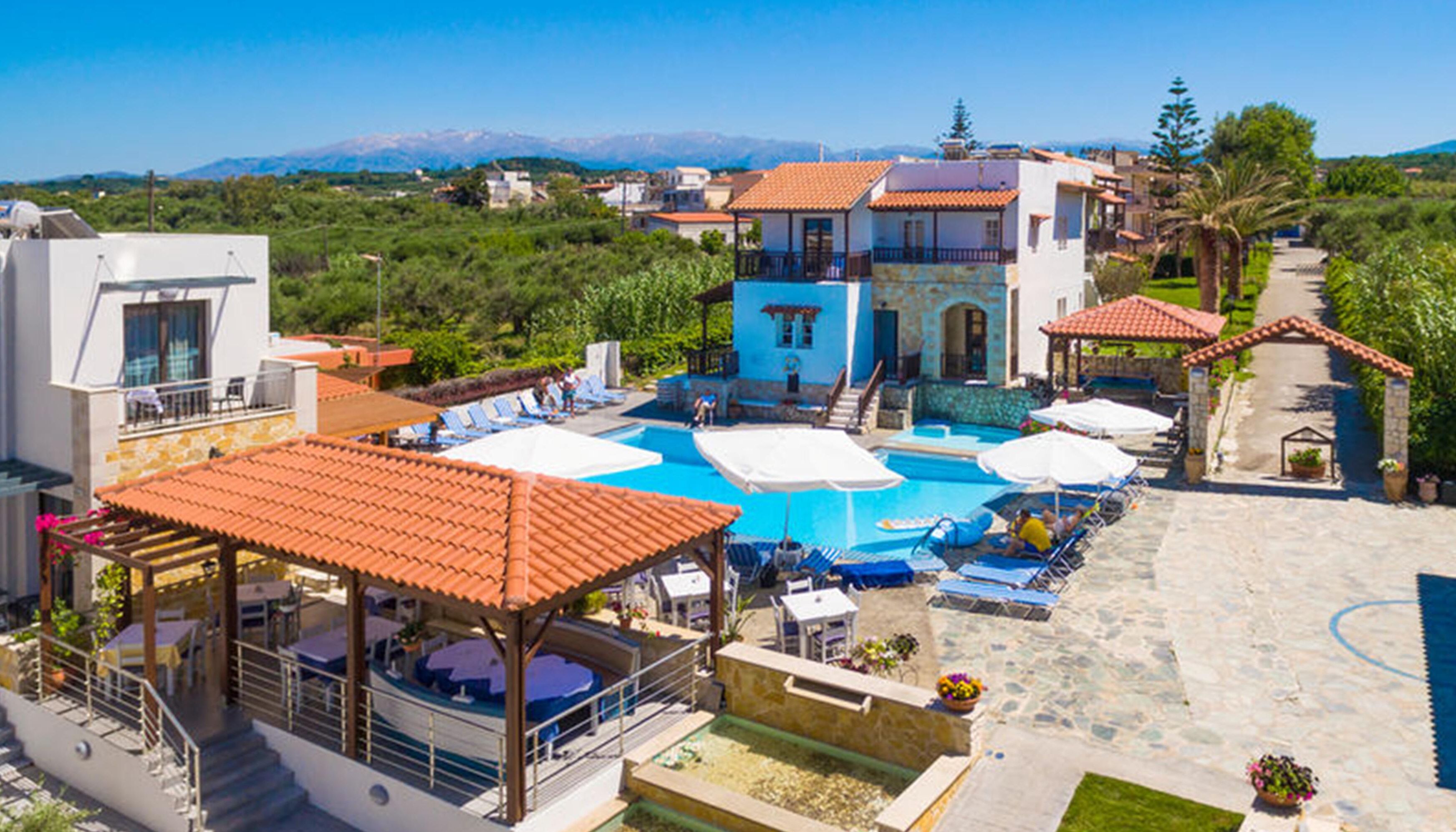 Resort com várias piscinas, áreas de estar ao ar livre e montanhas ao fundo.