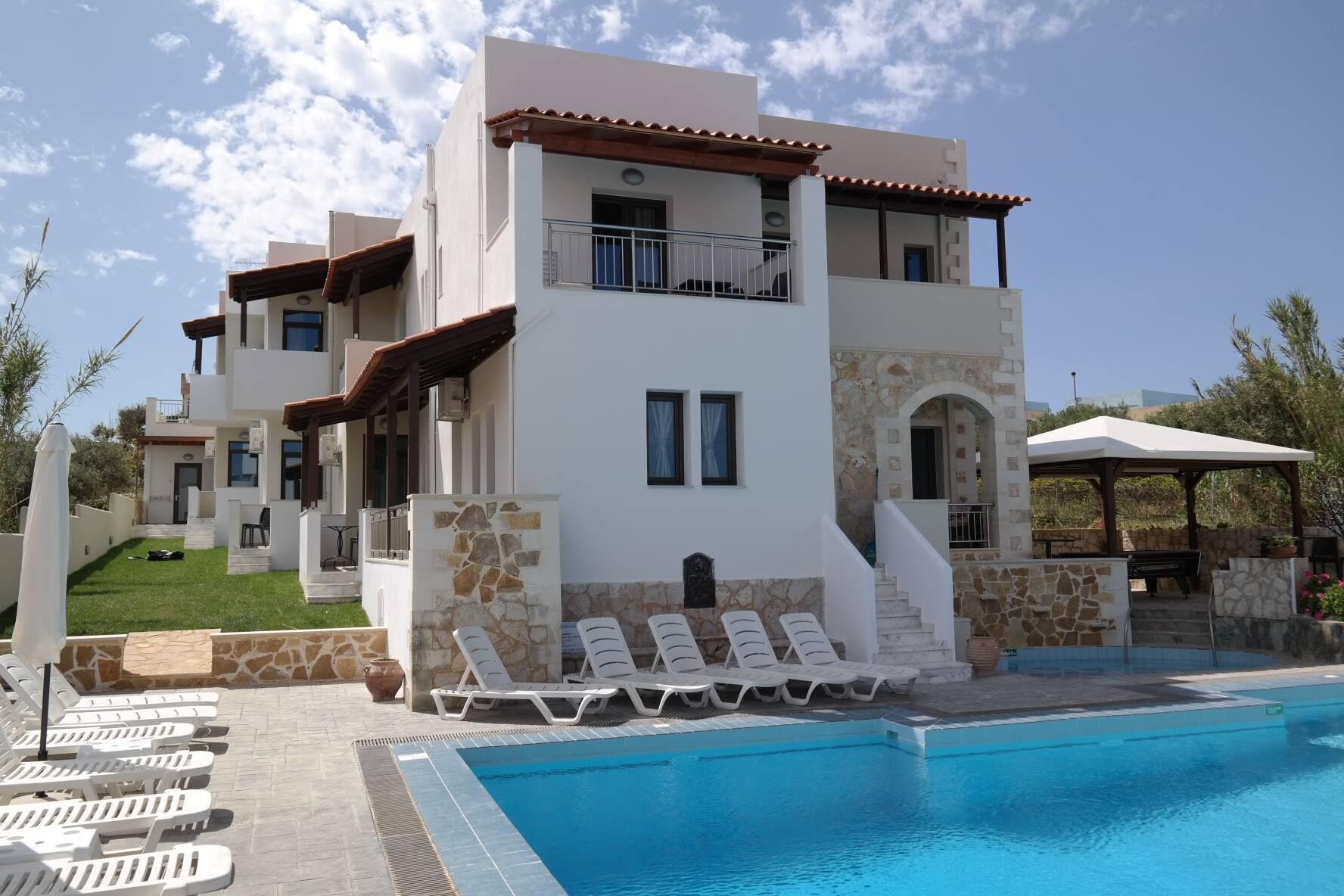 Um hotel moderno de dois andares com piscina, área de estar ao ar livre e fachada de pedra.