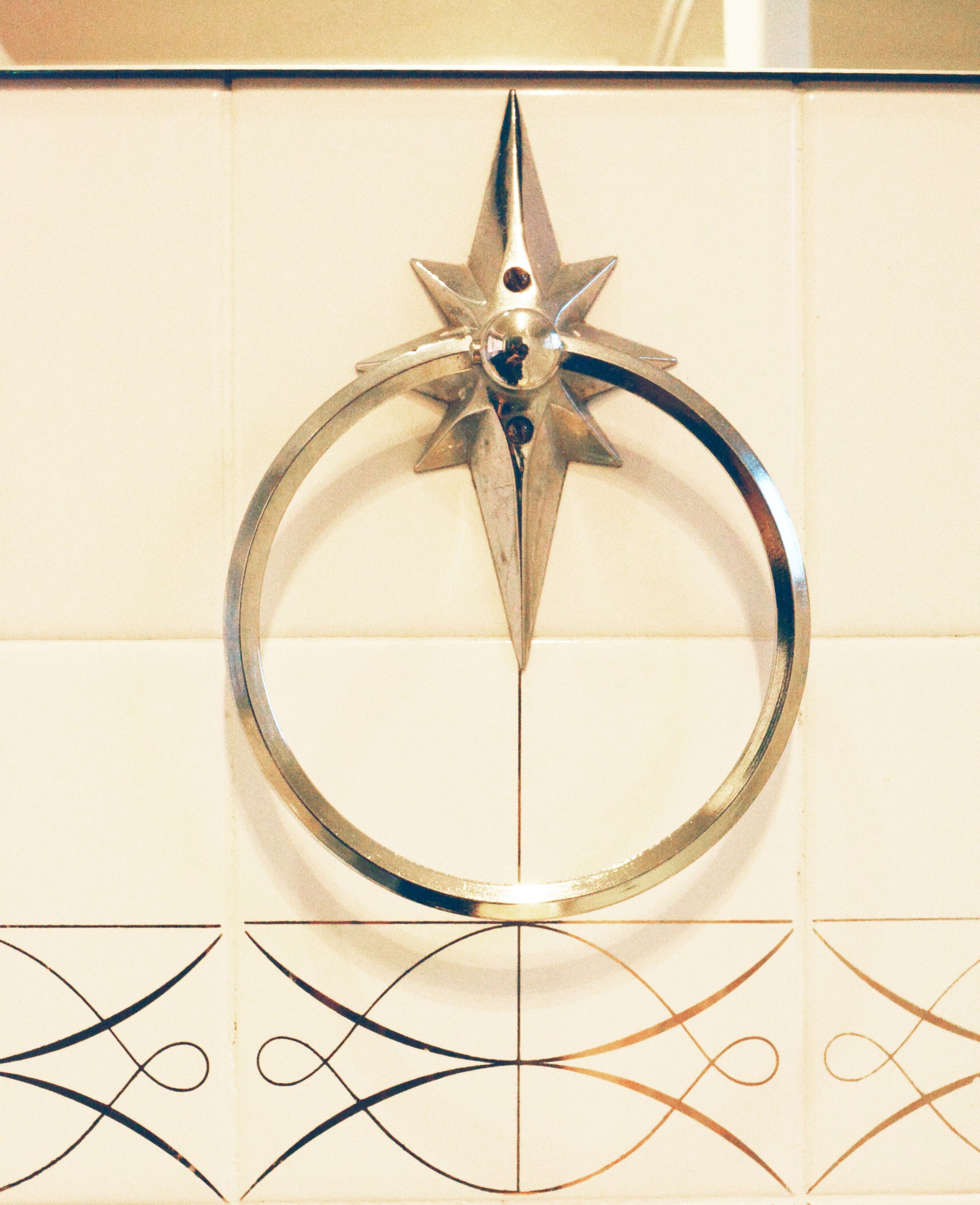 Uma bússola fixada na parede, com um topo em formato de estrela e uma base circular.