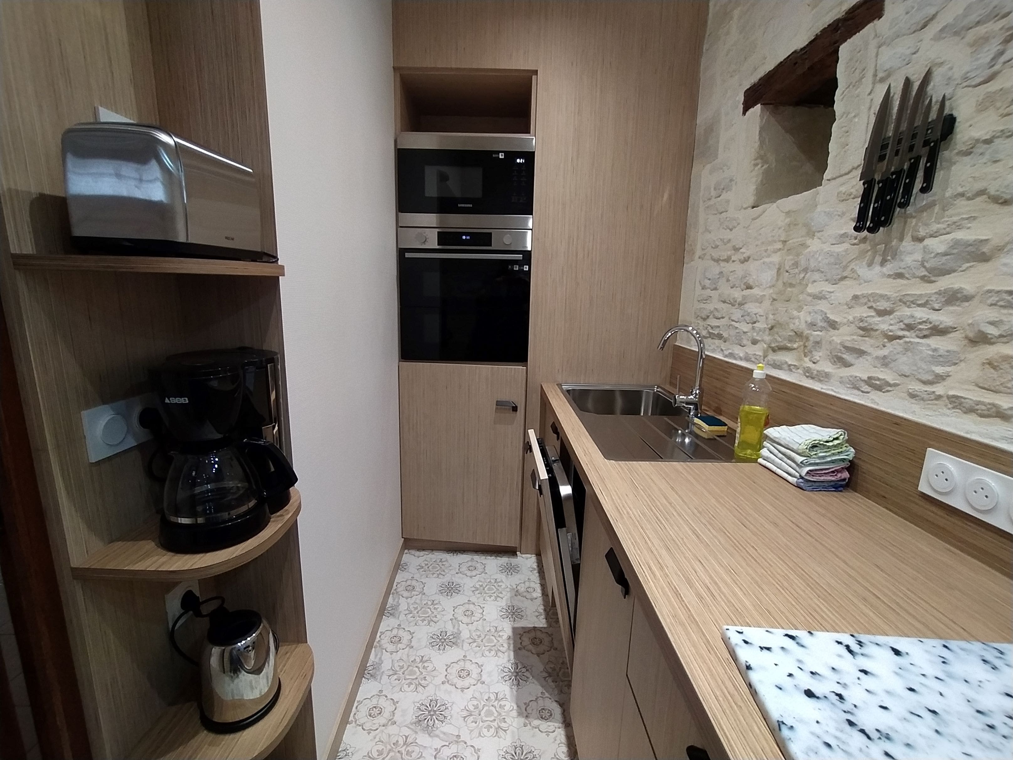Uma cozinha compacta com forno embutido, cafeteira e pia.