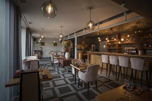 Um restaurante moderno com área de bar, mesas de jantar e banquetas.