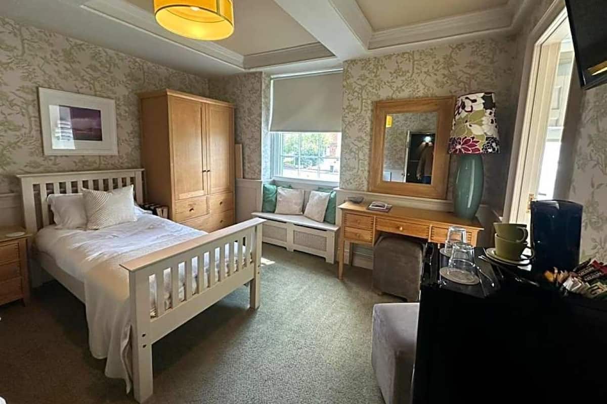 Quarto com cama, escrivaninha, cadeira, guarda-roupa e janela.