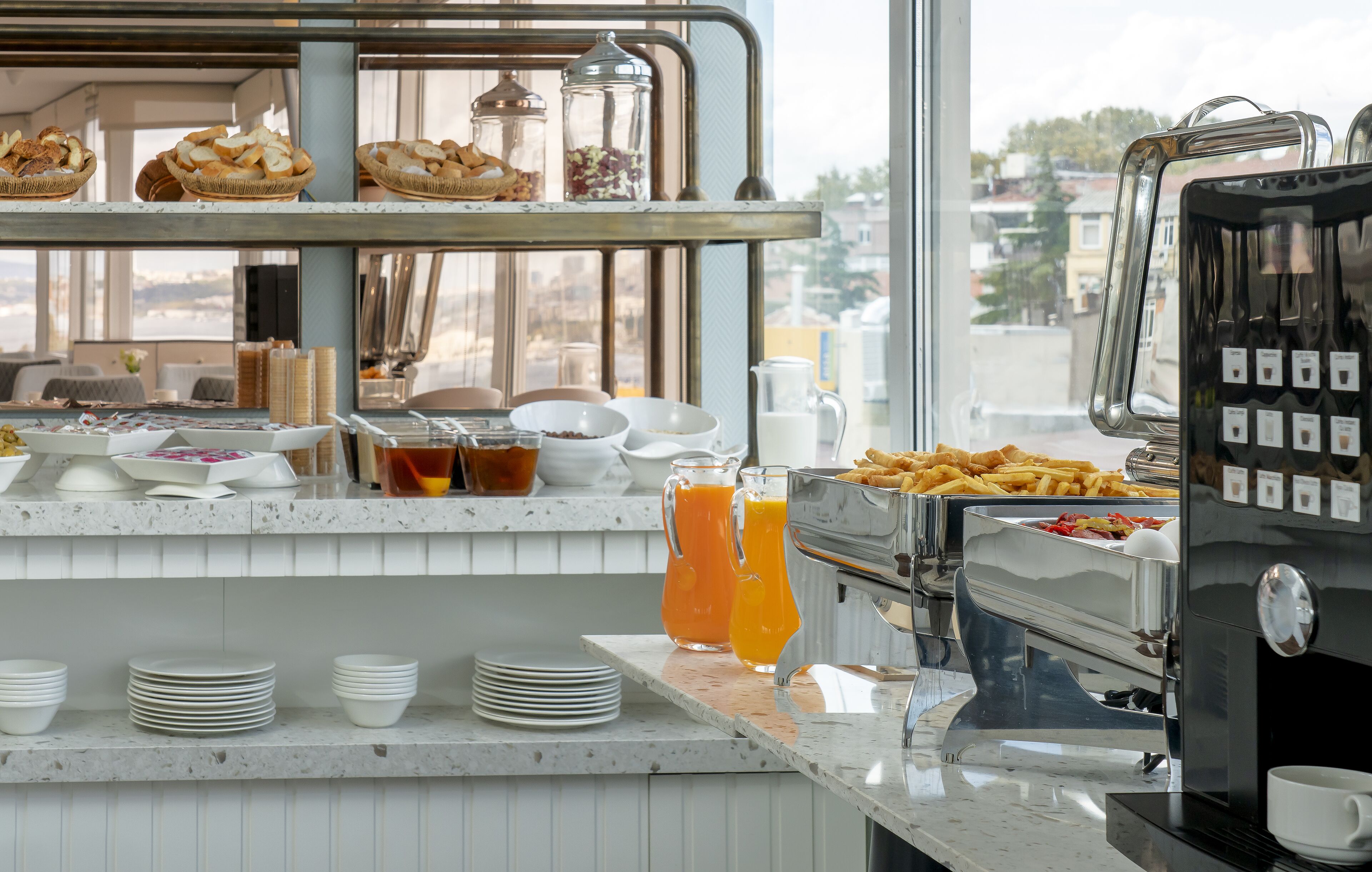 Disposição de buffet com diversos alimentos, uma máquina de café e um dispensador de suco.