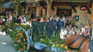 Um carro alegórico de parade com um cavalo e dois touros negros grandes, cercado por espectadores.