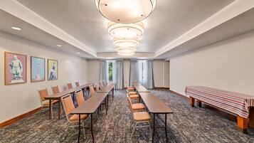 Uma sala de conferências com mesas compridas, cadeiras e um banco.