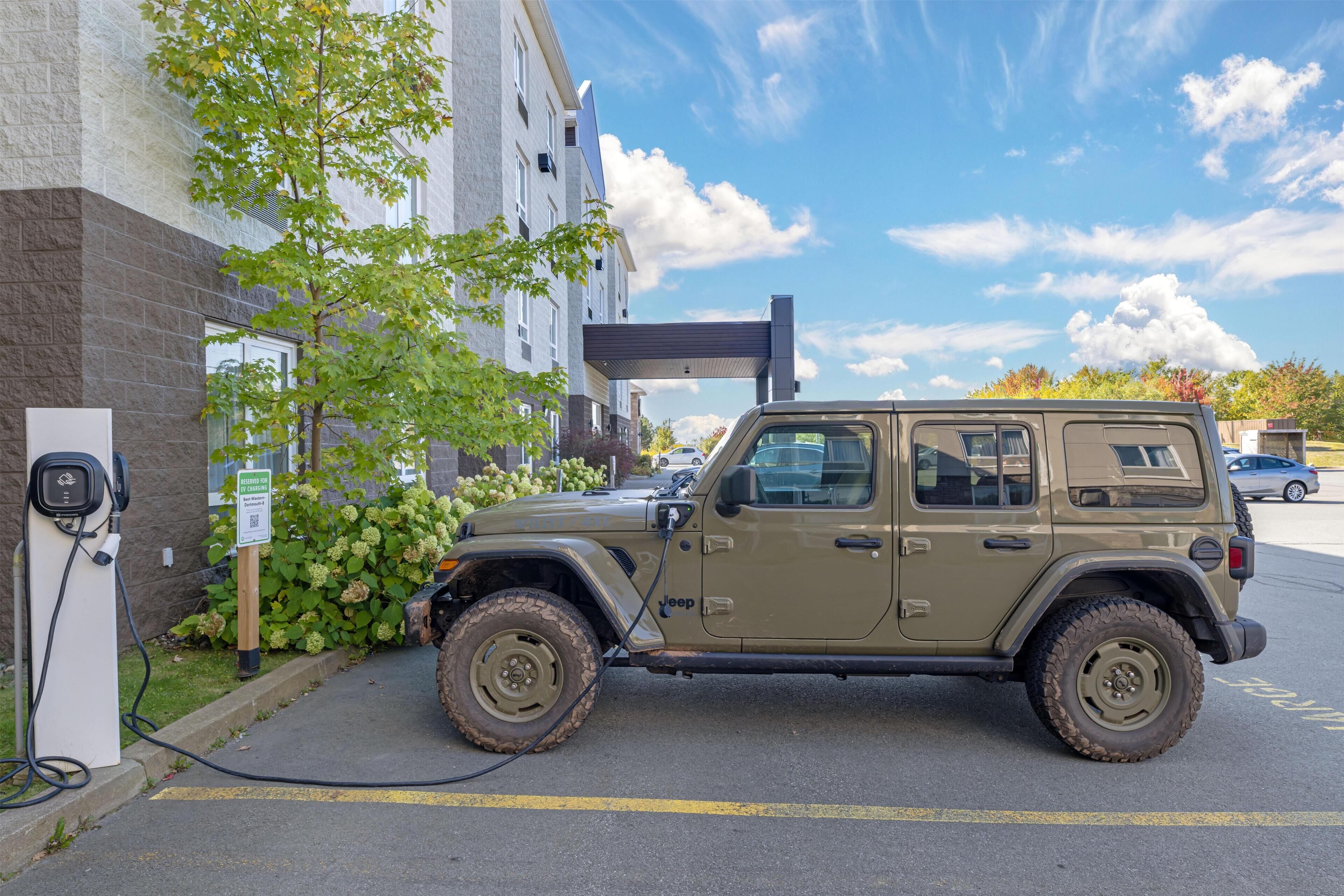Um Jeep estacionado em uma estação de carregamento elétrico em um estacionamento.