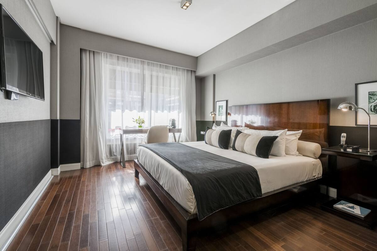 Quarto de hotel moderno com uma cama grande, uma escrivaninha e uma cadeira.